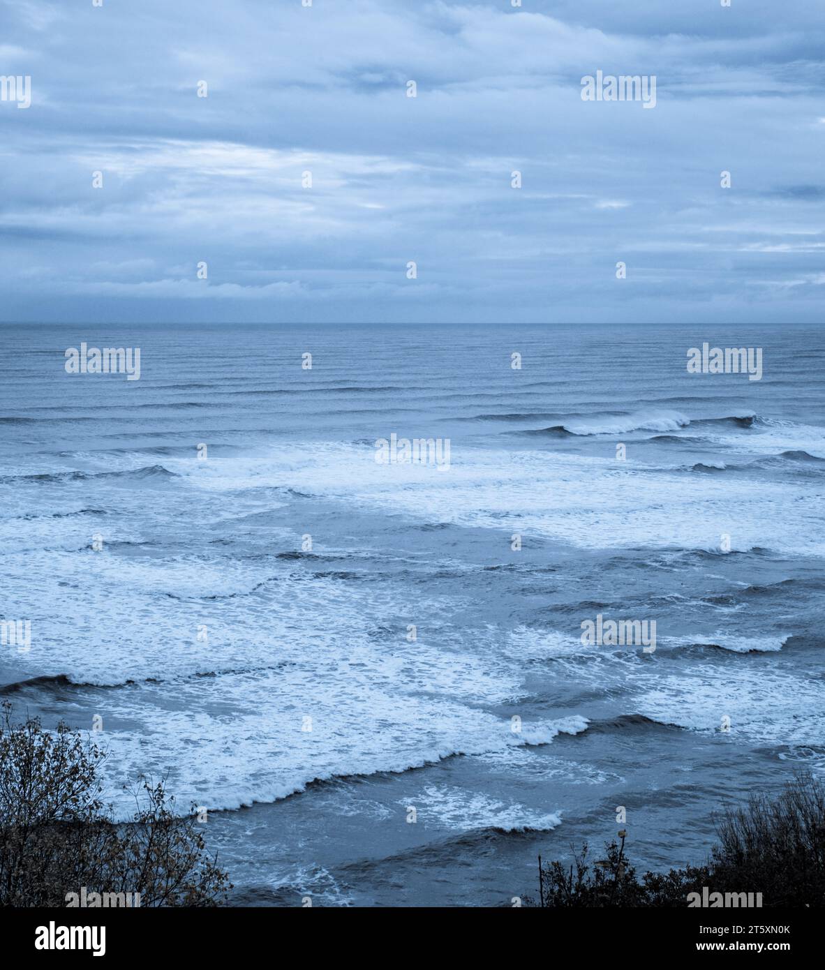Waves breaking on the beach from the cliff tops at Robin Hood's Bay in ...