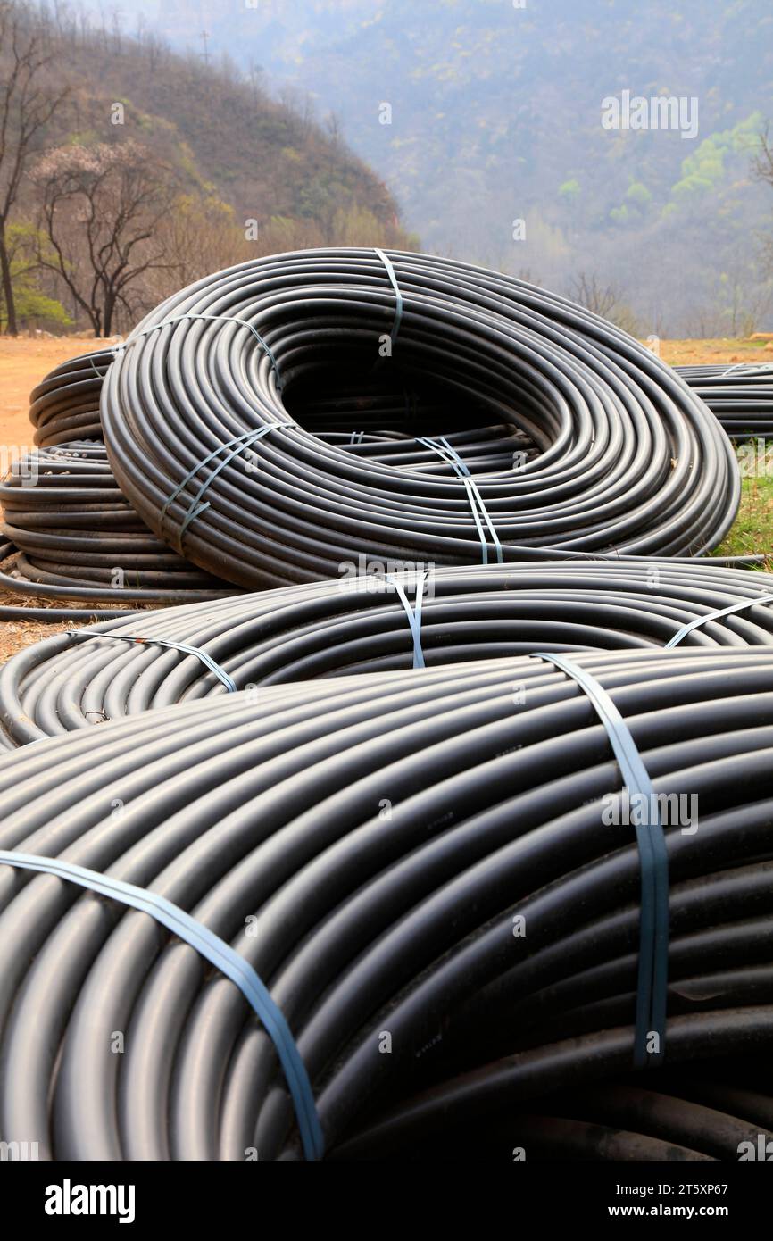 Black plastic pipe curled up together Stock Photo - Alamy