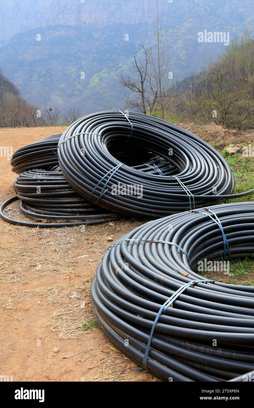 Black plastic pipe curled up together Stock Photo - Alamy