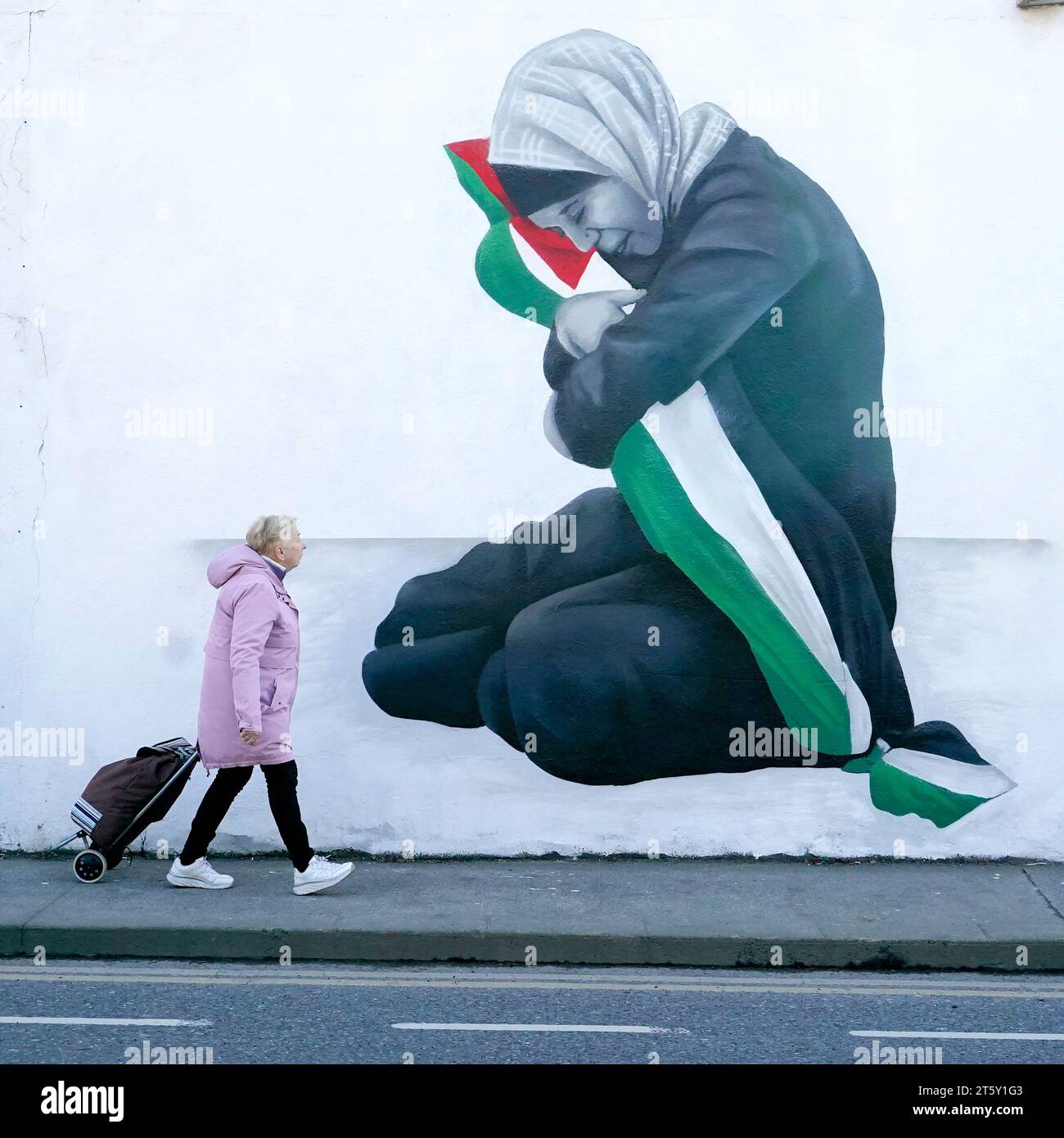 A woman walks past a pro-Palestine mural by the artist Emmalene Blake ...