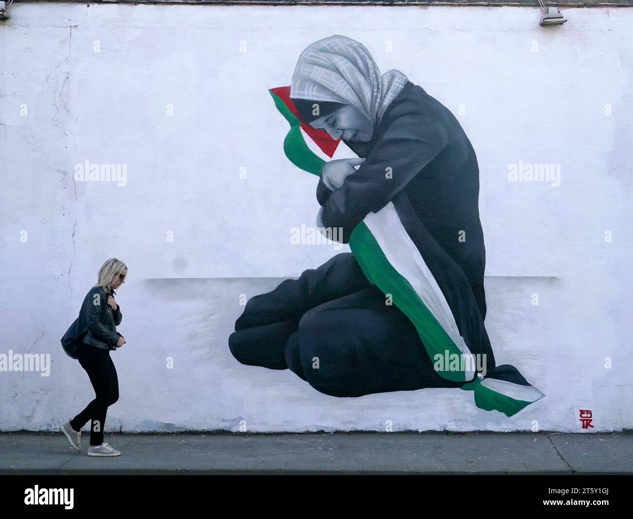 A woman walks past a pro-Palestine mural by the artist Emmalene Blake ...