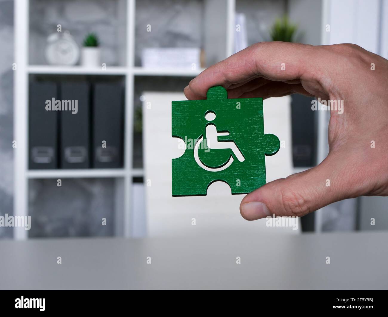 A hand holds a puzzle piece with a disabled person sign. An inclusive ...