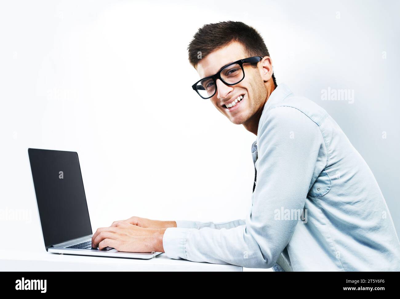 Portrait, business man typing on laptop at table and isolated on white ...
