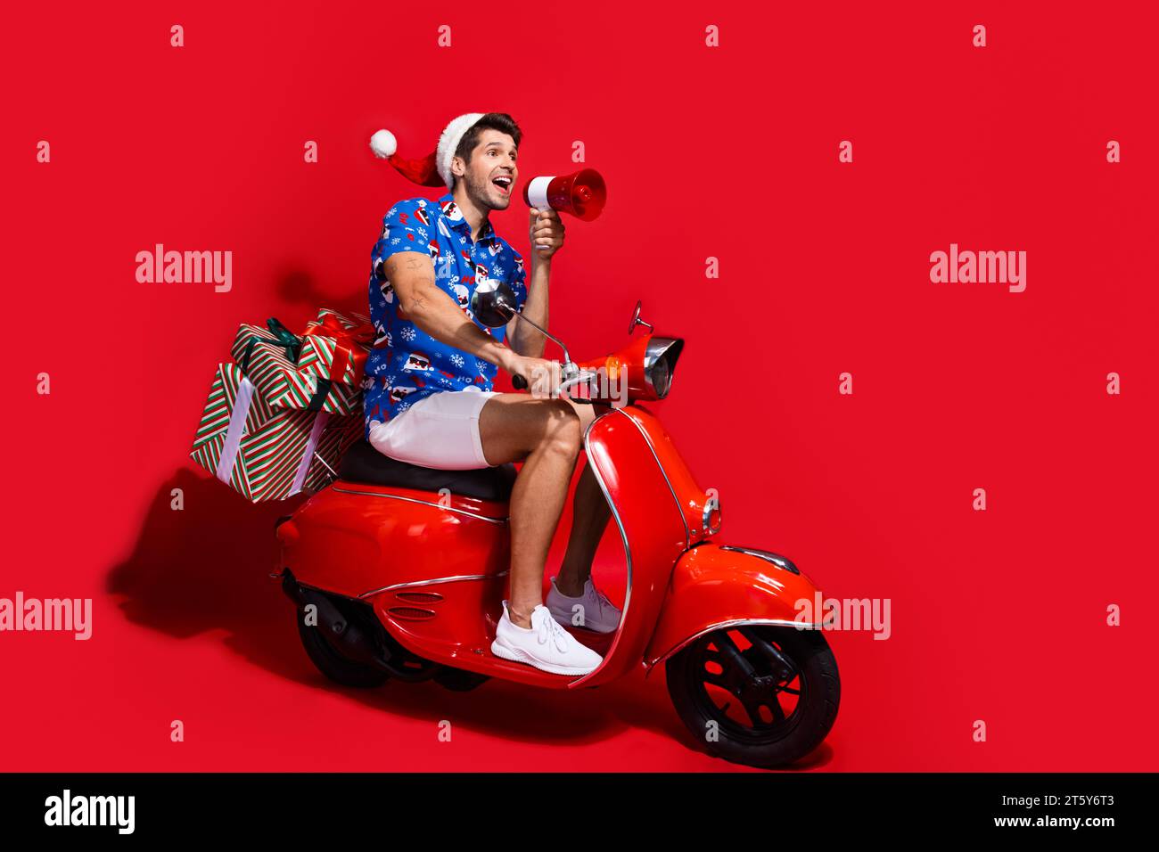 Full size photo of funky young man drive moped megaphone dressed santa ...