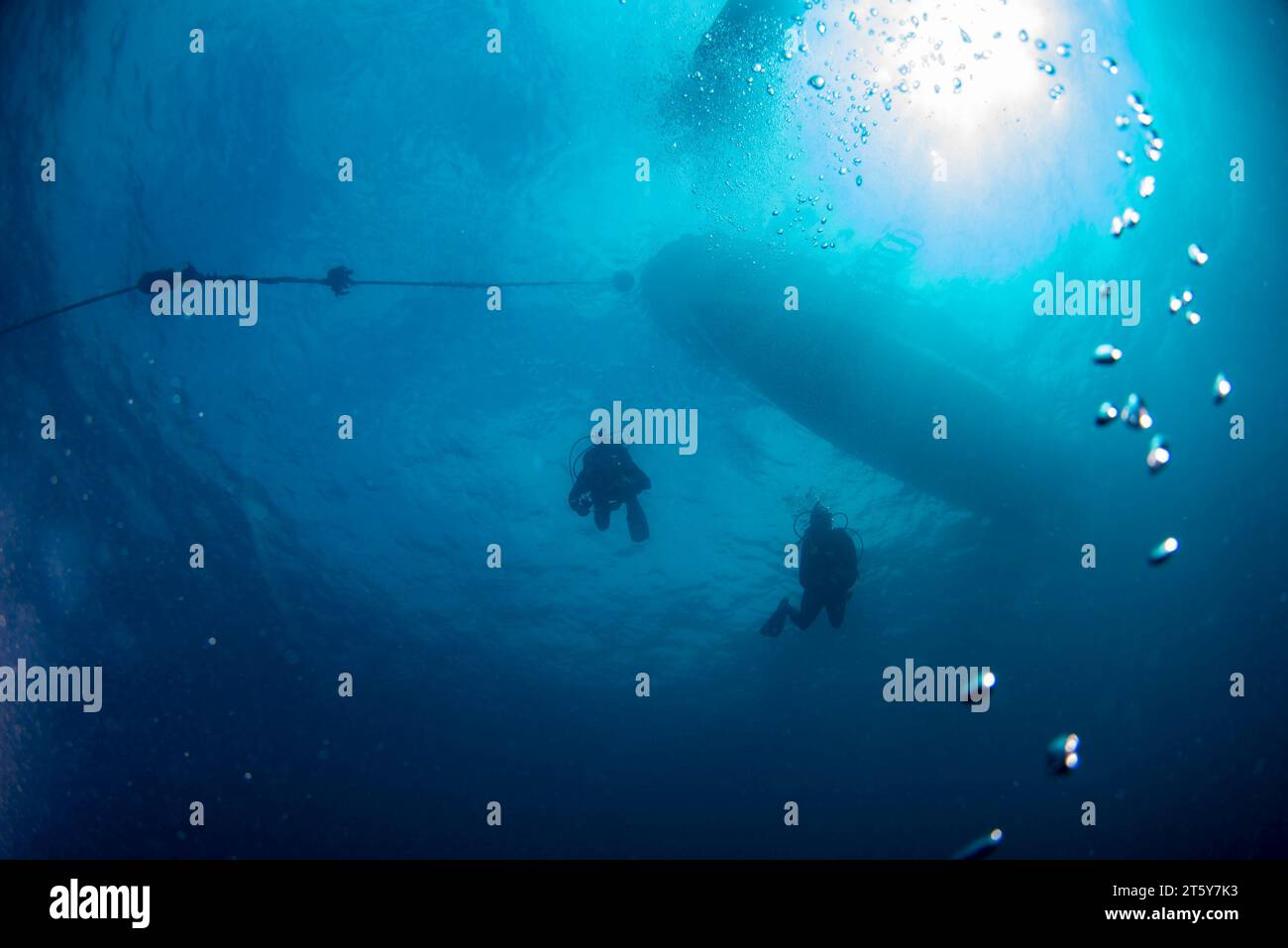 Some scuba divers under the boat in the blue sea Underwater shot with ...