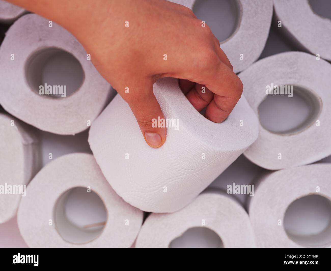 A person hand taking a toilet roll from heap of toilet paper rolls ...