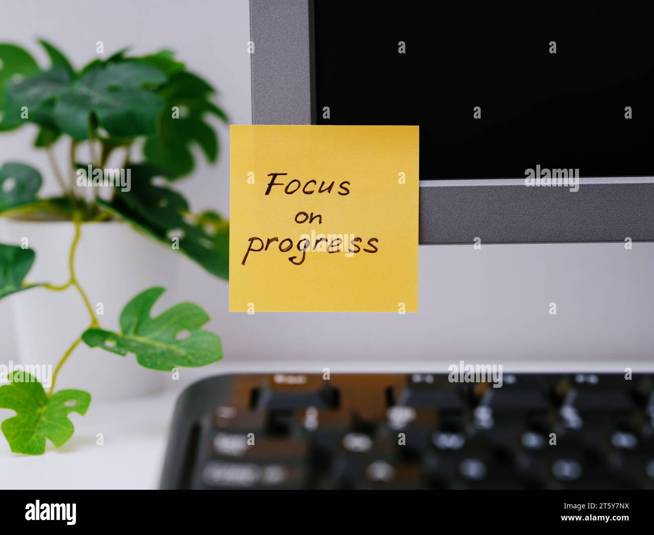 A yellow paper notes with the reminder Focus on Progress on it sticked ...