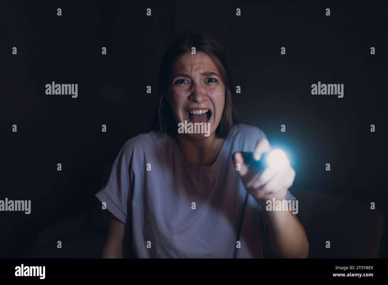 Woman scared holding hand flashlight in dark and afraid of violence ...