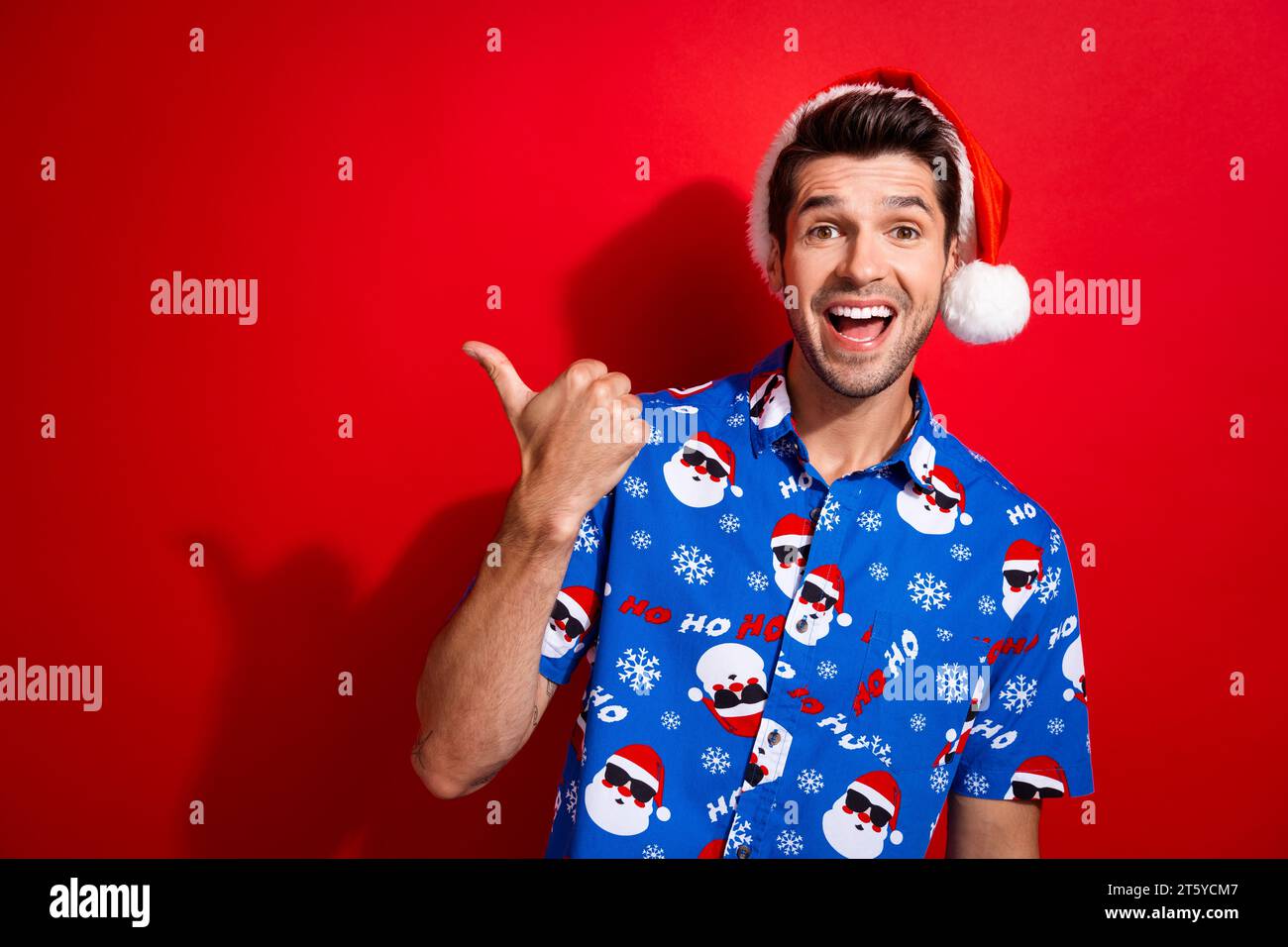 Photo of ecstatic funky guy wear santa hat print shirt indicating at ...