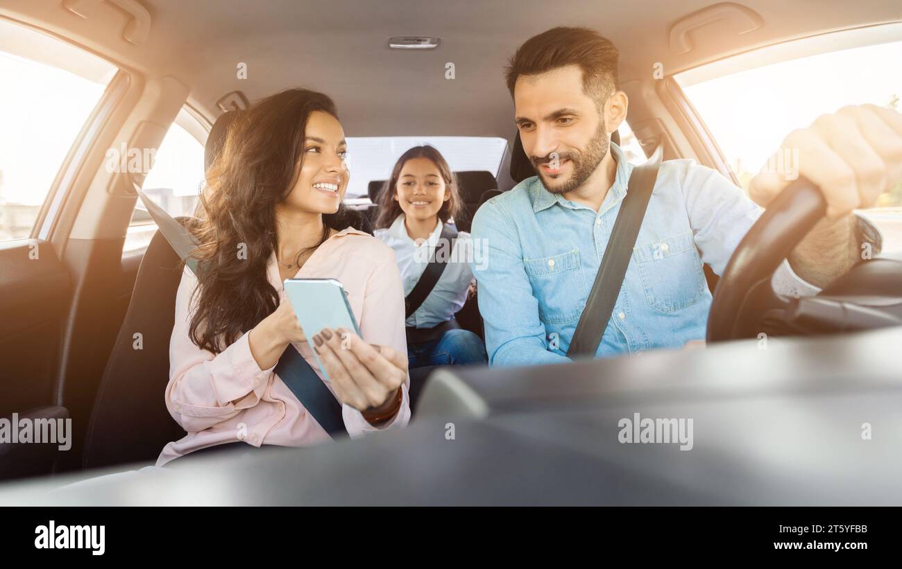 Family enjoying a car ride with mother holding a phone and child ...