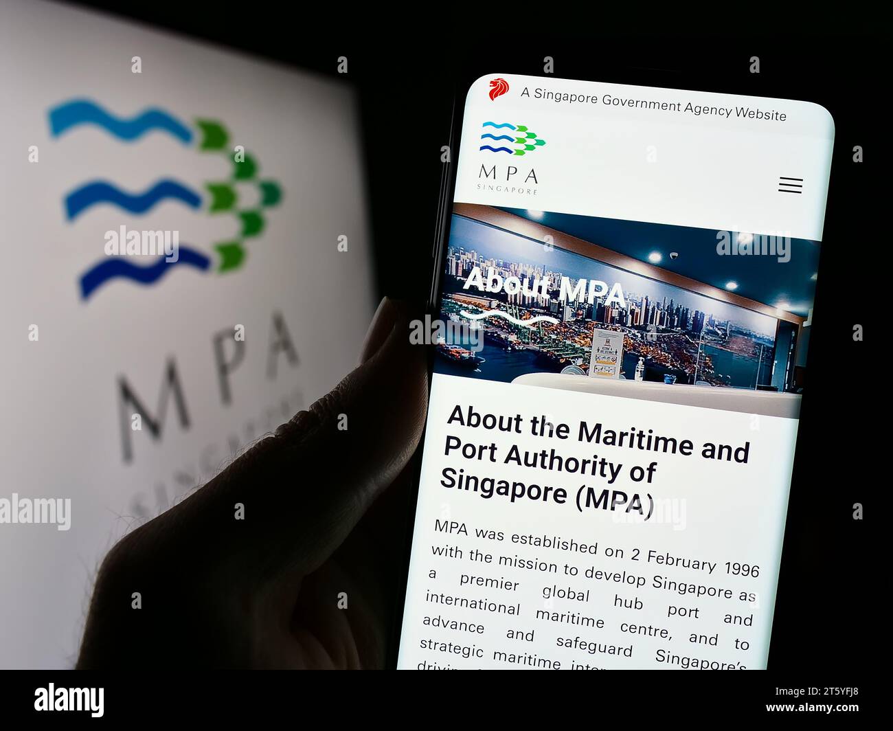 Person holding cellphone with webpage of Maritime and Port Authority of ...