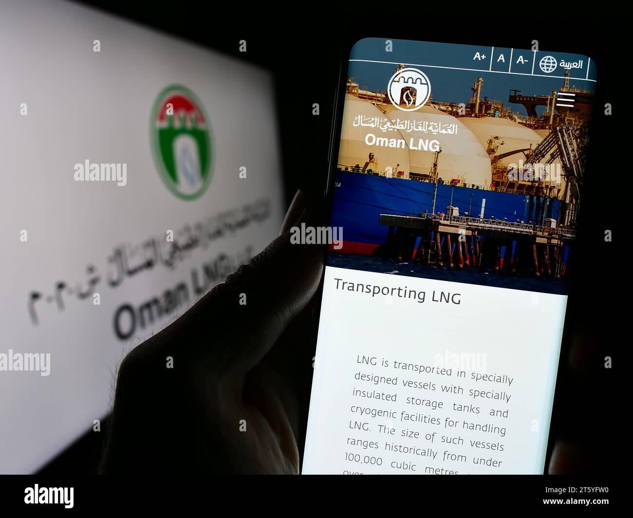 Person holding smartphone with website of Omani liquefied natural gas company Oman LNG in front ...