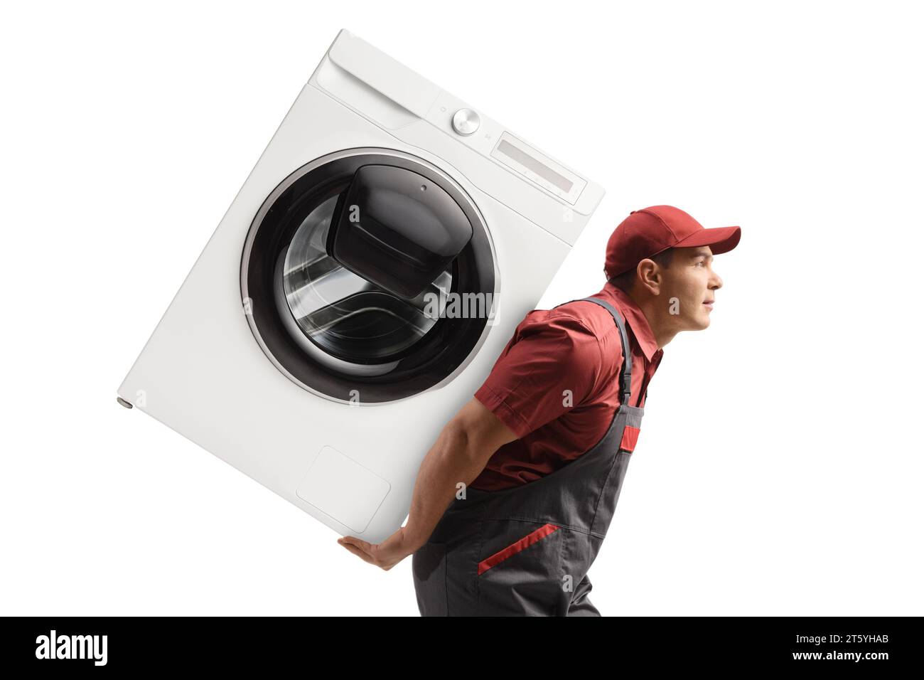 Profile shot of a worker in a uniform carrying a washing machine on his ...