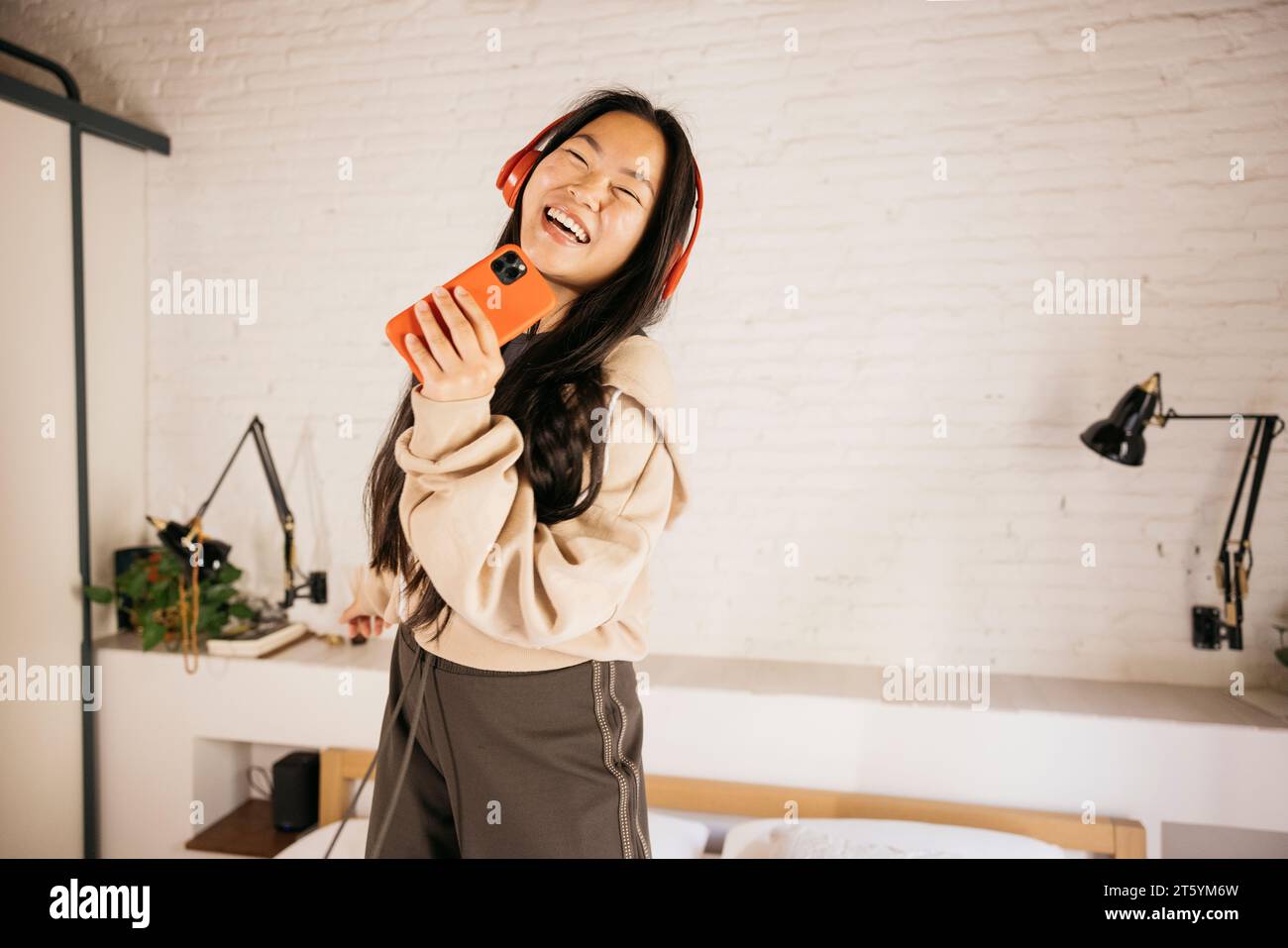 Young chinese woman listening music with headphones and using a phone ...