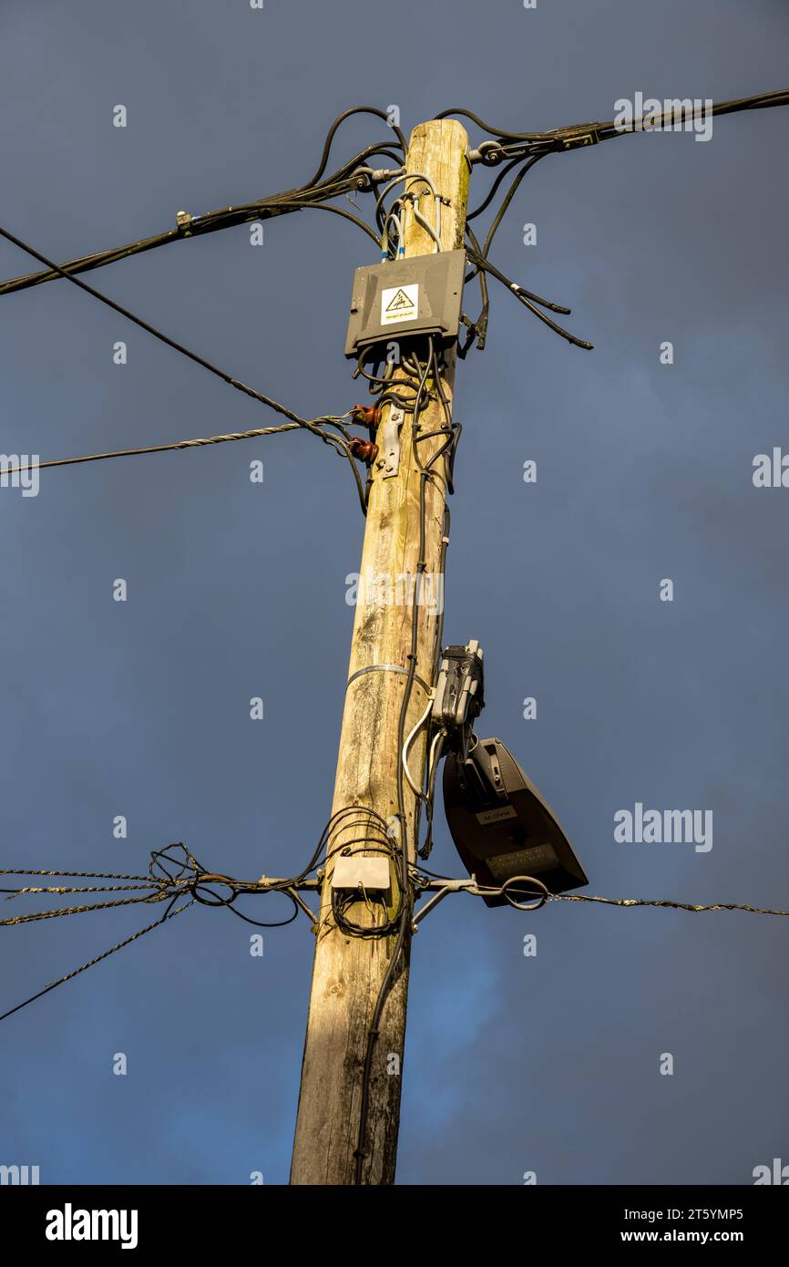Telegraph pole catching late afternoon sun as storm clouds and rain ...