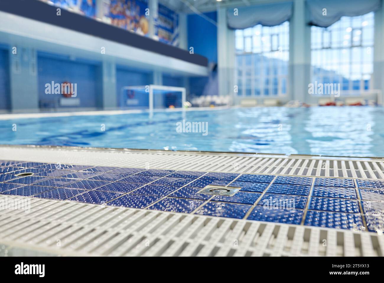 Focus on wet floor of blue poolside with white plastic grid against ...