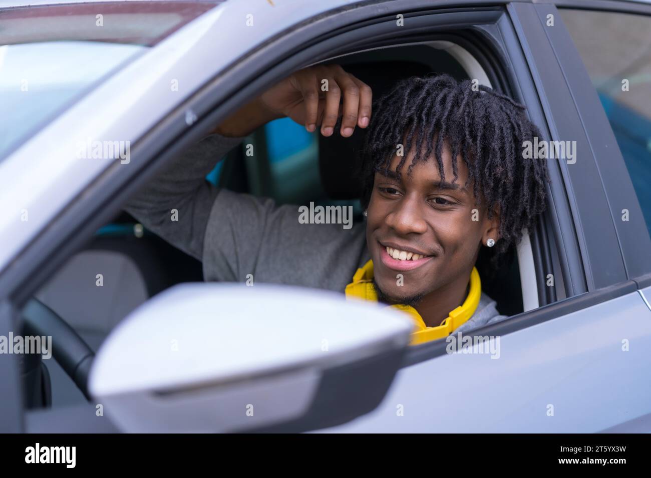Side view portrait of a happy african young man sitting inside a car ...