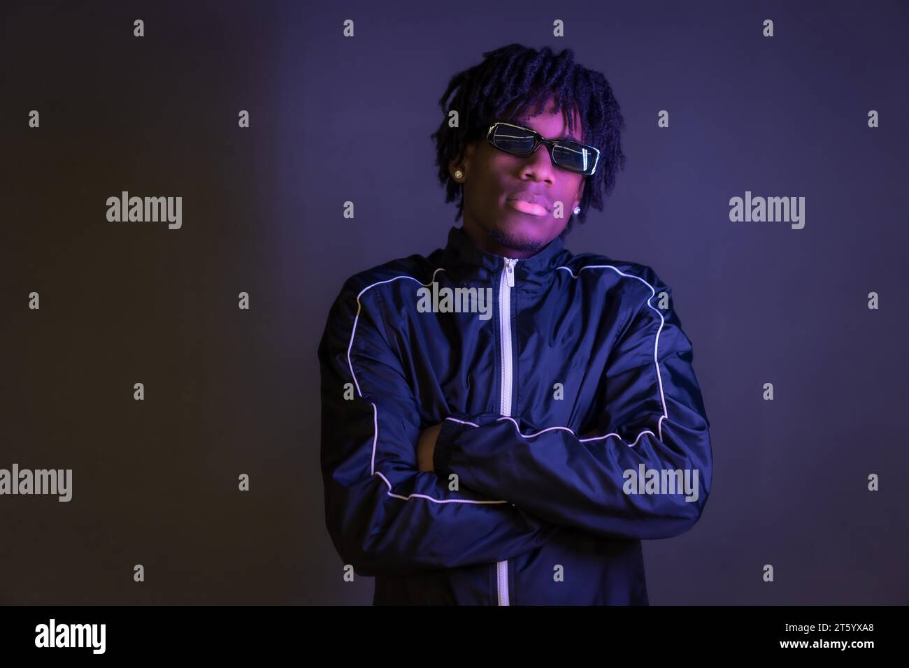 Dark studio portrait of a proud african young artist standing with arms ...