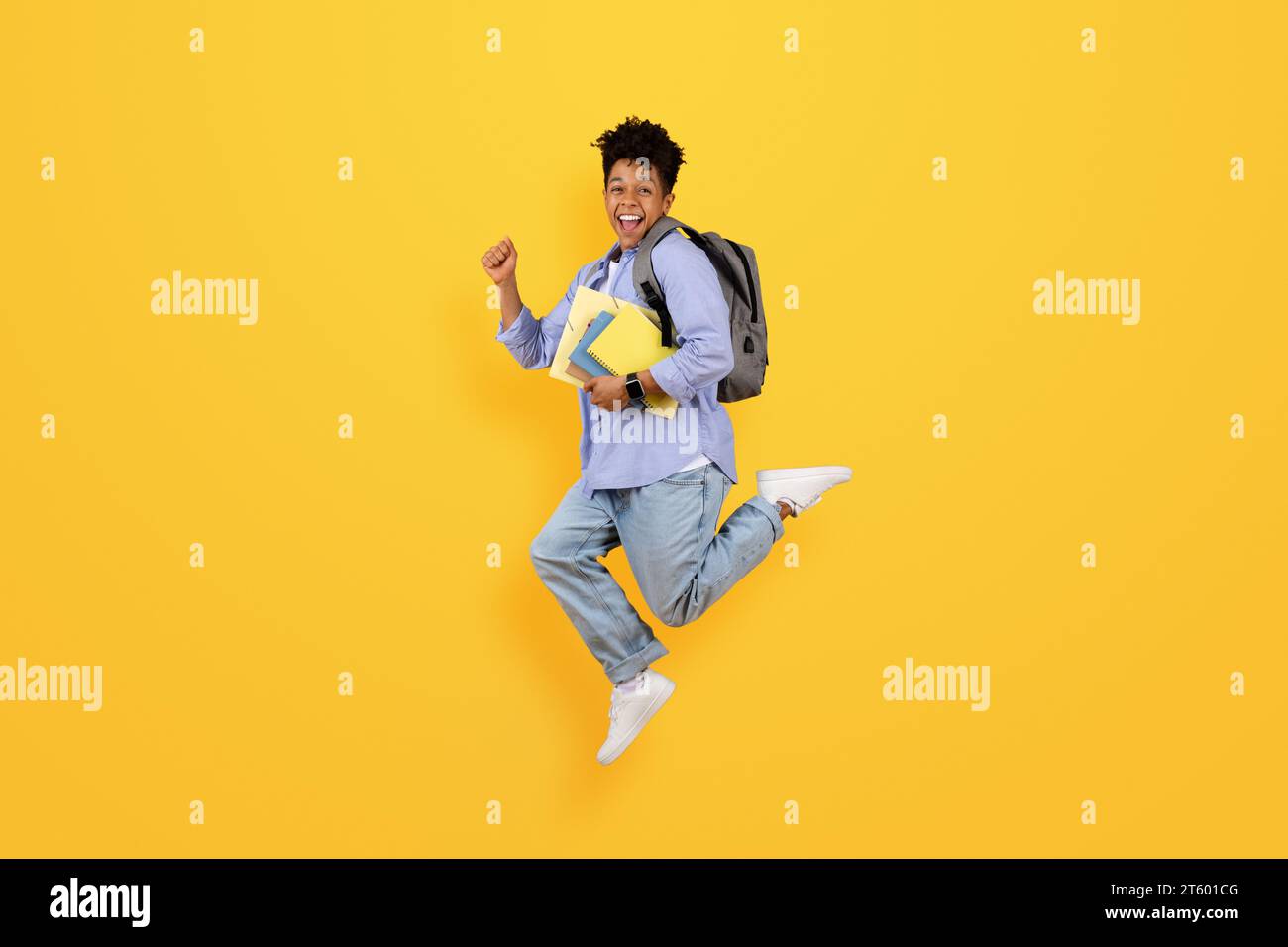 Student jumps in excitement, holding books and smiling Stock Photo - Alamy