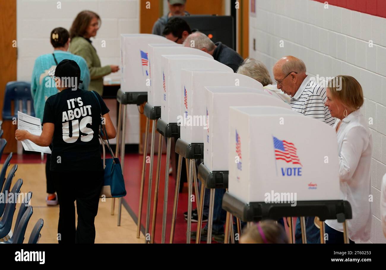 A voter, left, carries her ballot to the counting machine after voting ...