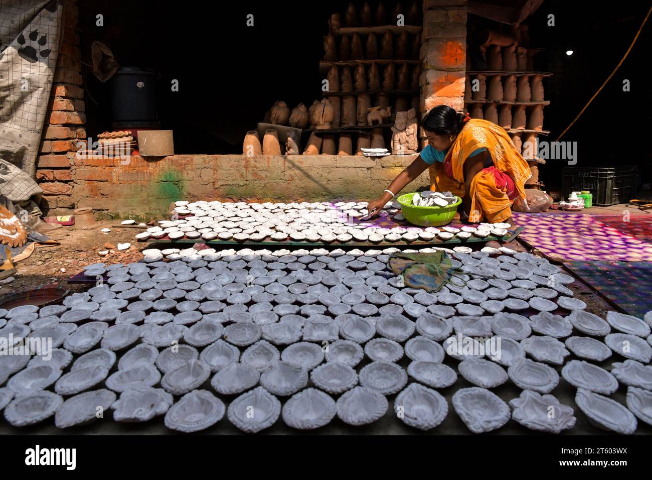 A woman is sorting earthen lamps before getting painted in the pottery ...
