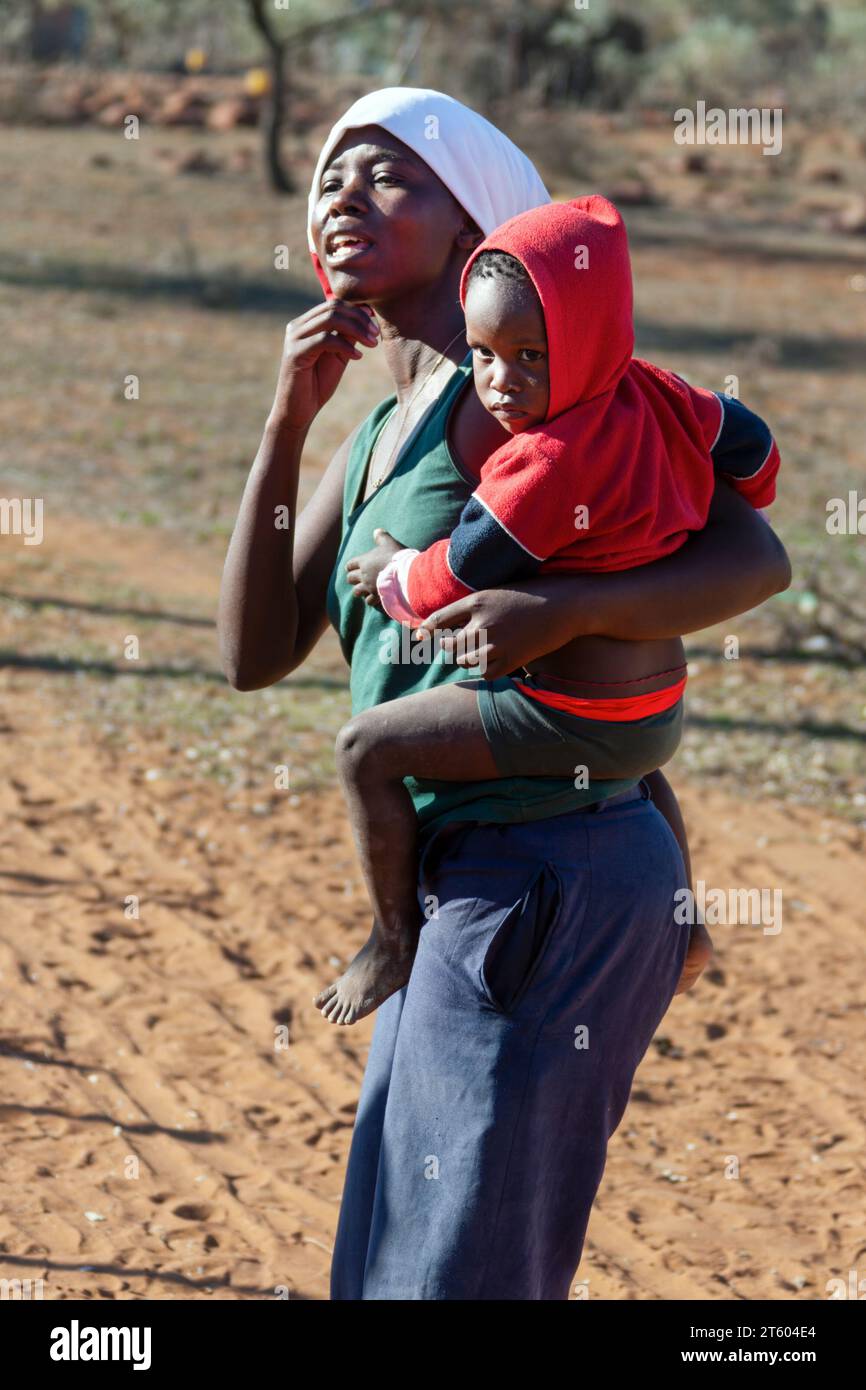 African mother carry a child with a hoodie in the yard, african village ...
