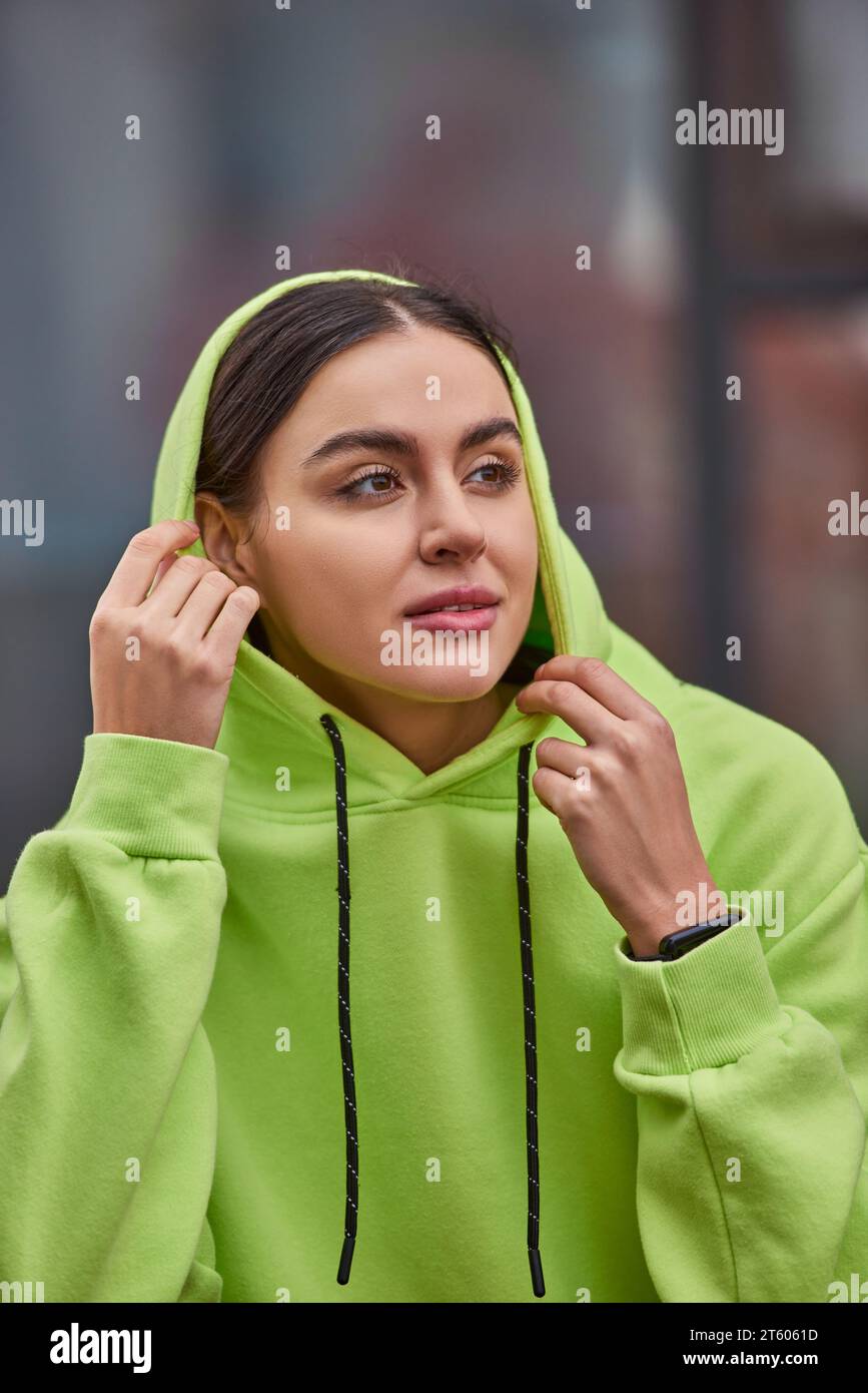 brunette young woman in lime color hoodie wearing hood on head and ...