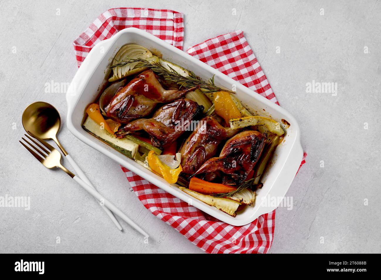 Whole quails baked with vegetables in white cooking dish. top view ...