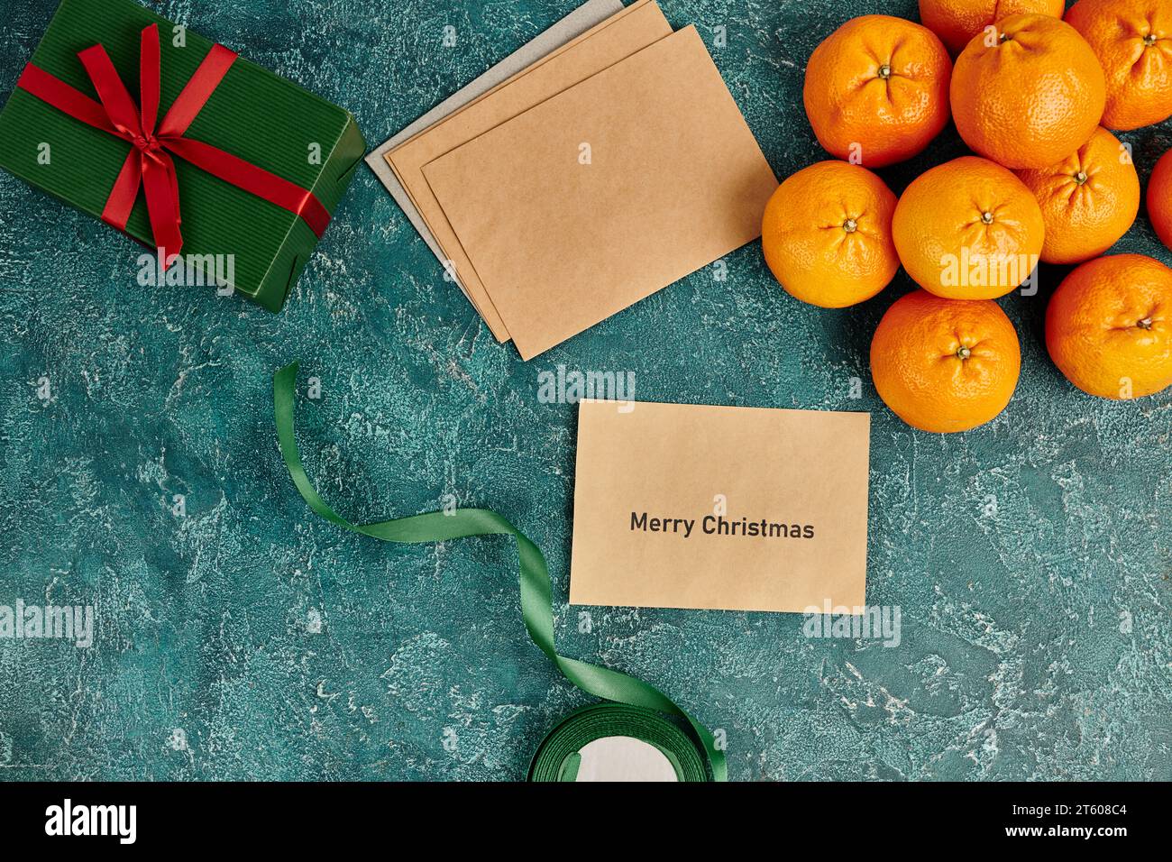 envelope with Merry Christmas lettering near tangerines and gift box ...