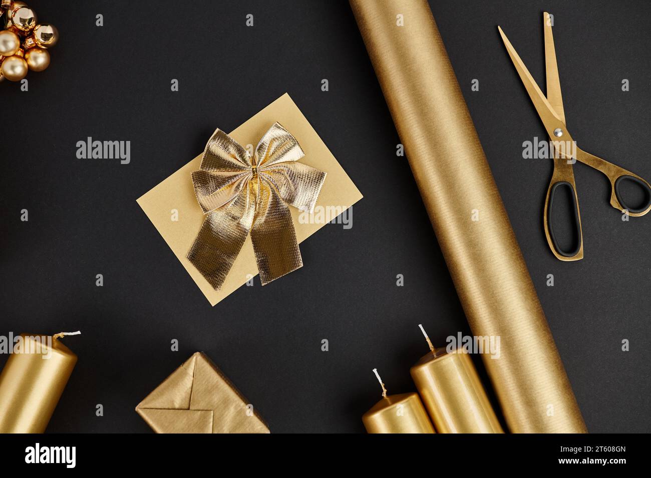 golden Christmas objects on black backdrop, scissors near rolled paper ...