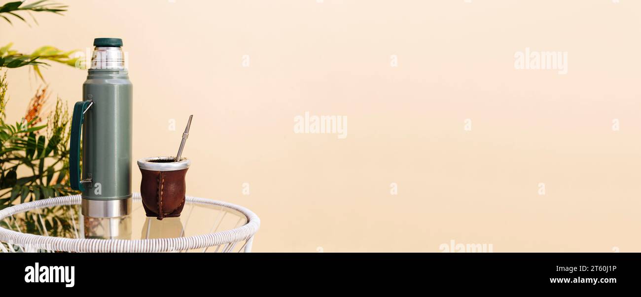 Thermos and calabash mate cup with straw. In the backyard over a glass ...