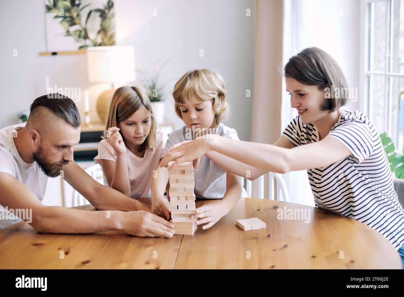 Loving young parents with little son and daughter enjoy playtime on leisure, play blocks removal ...