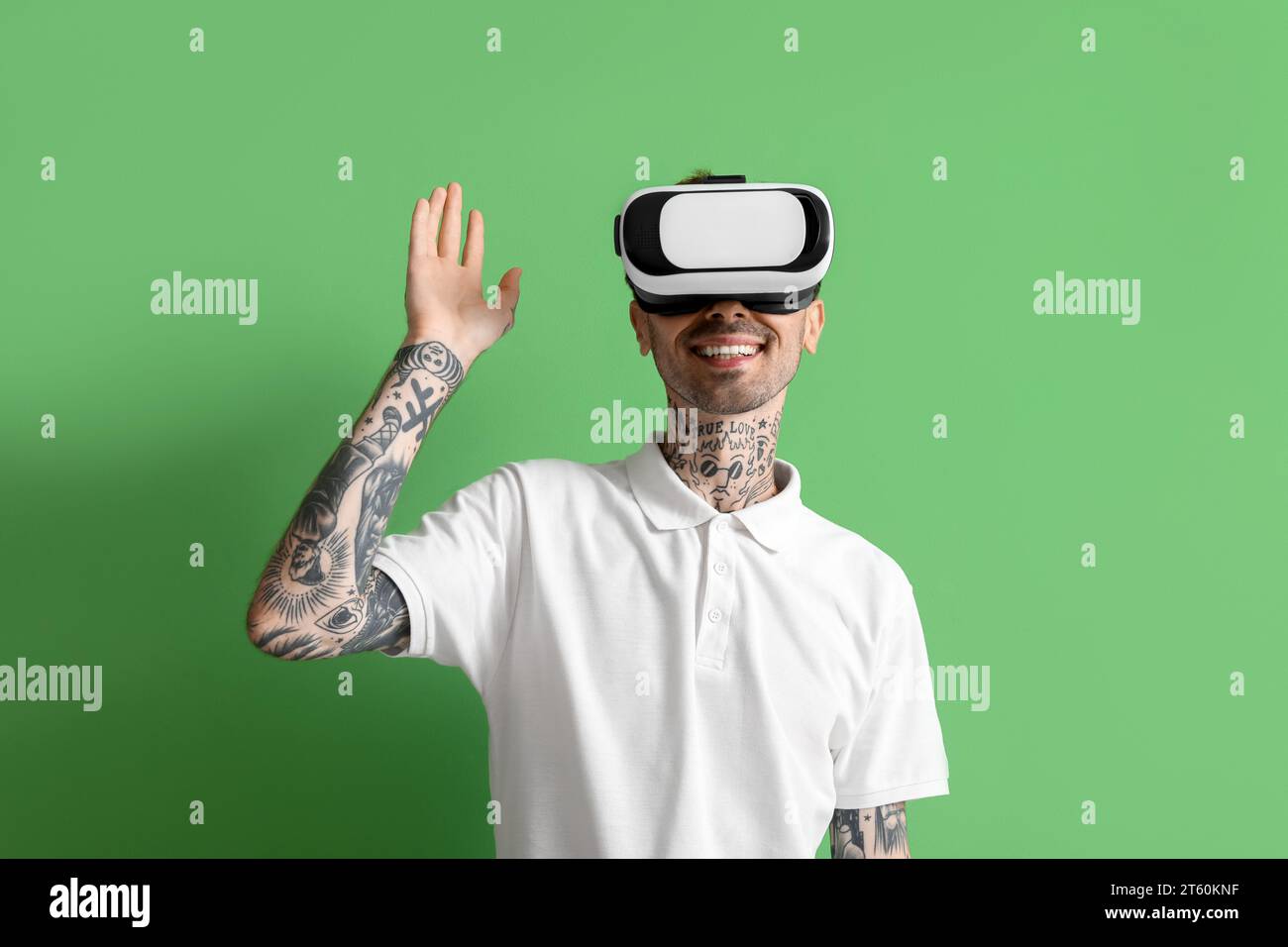 Happy young man in VR headset waving hand on green background Stock ...