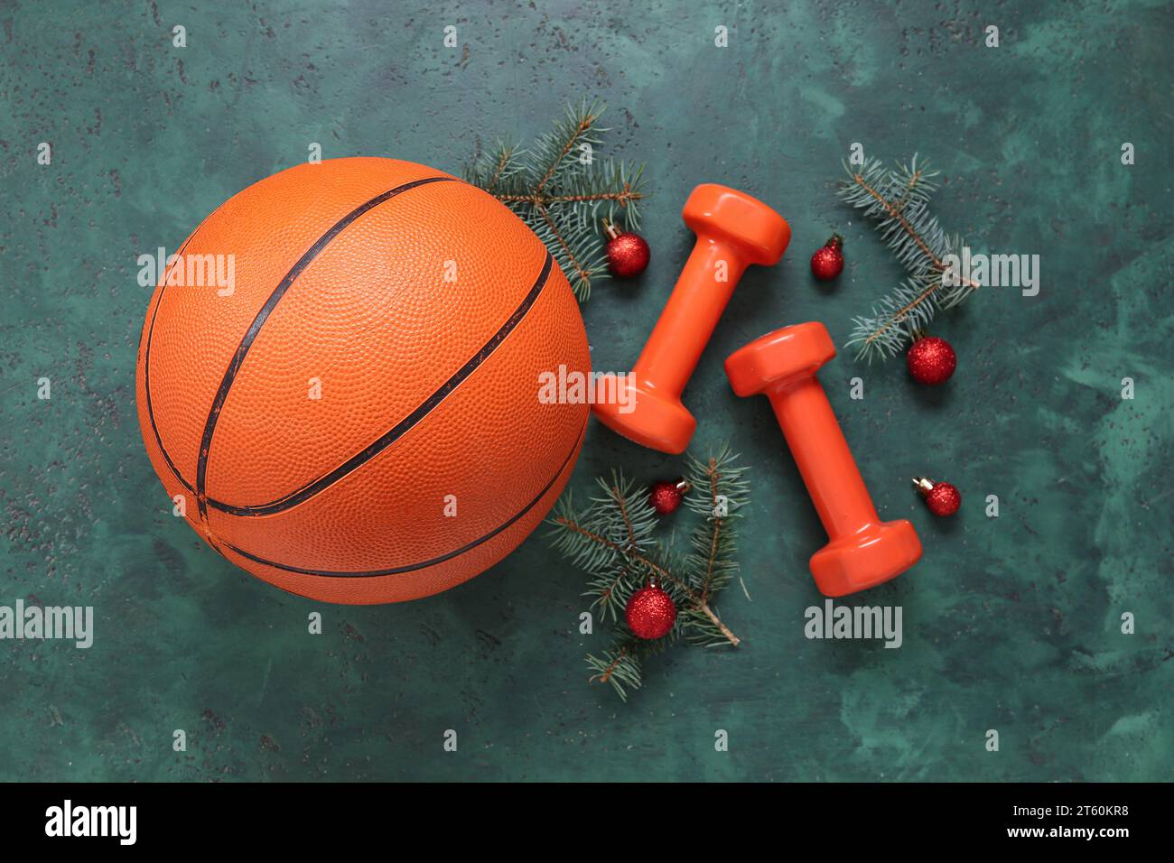 Composition with basketball ball, dumbbells and Christmas tree branches ...