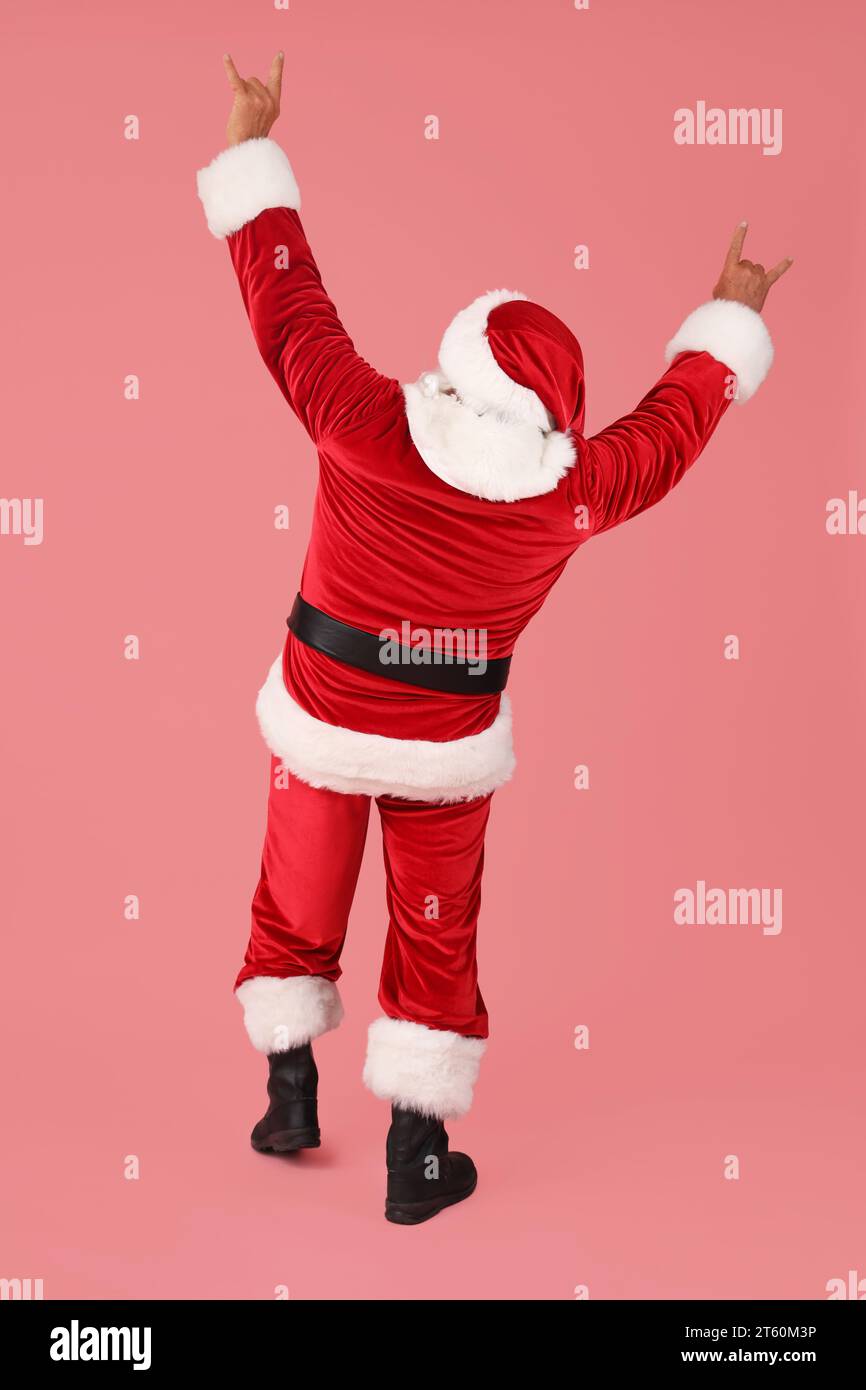 Cool Santa Claus showing "devil horns" on pink background, back view ...