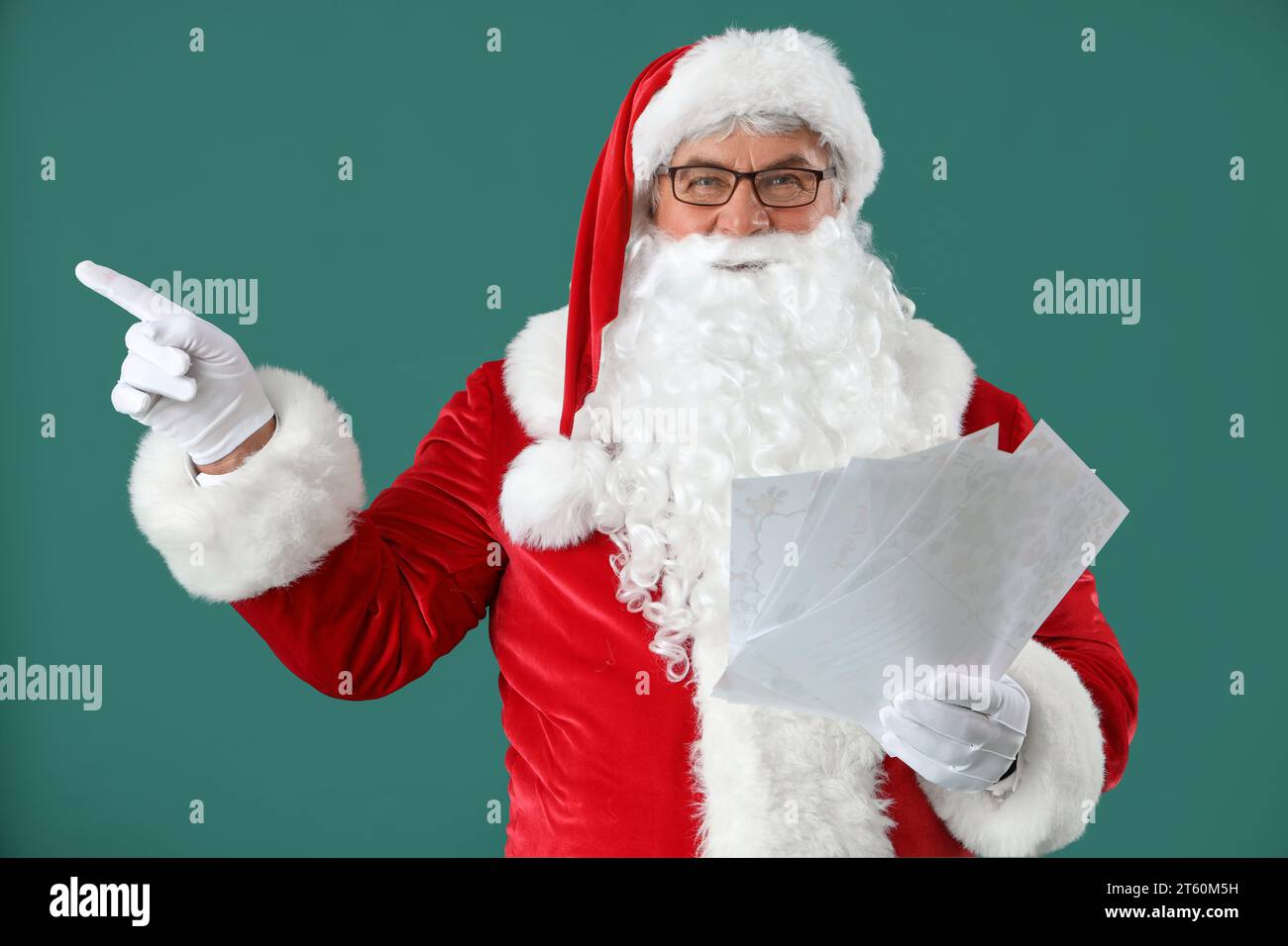 Santa Claus with letters pointing at something on green background ...