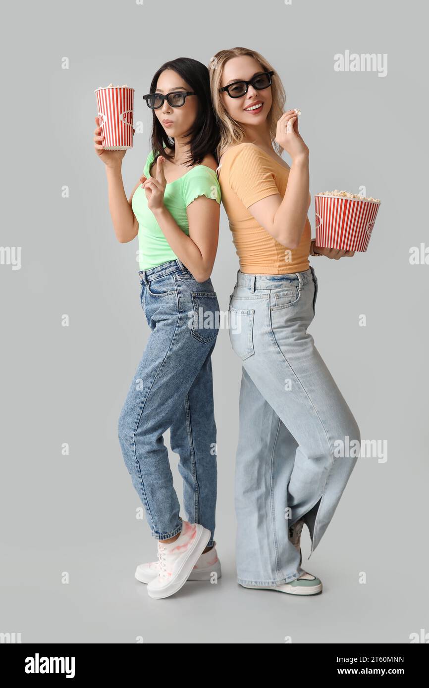 Beautiful young women in 3D glasses with buckets of popcorn on white background Stock Photo - Alamy