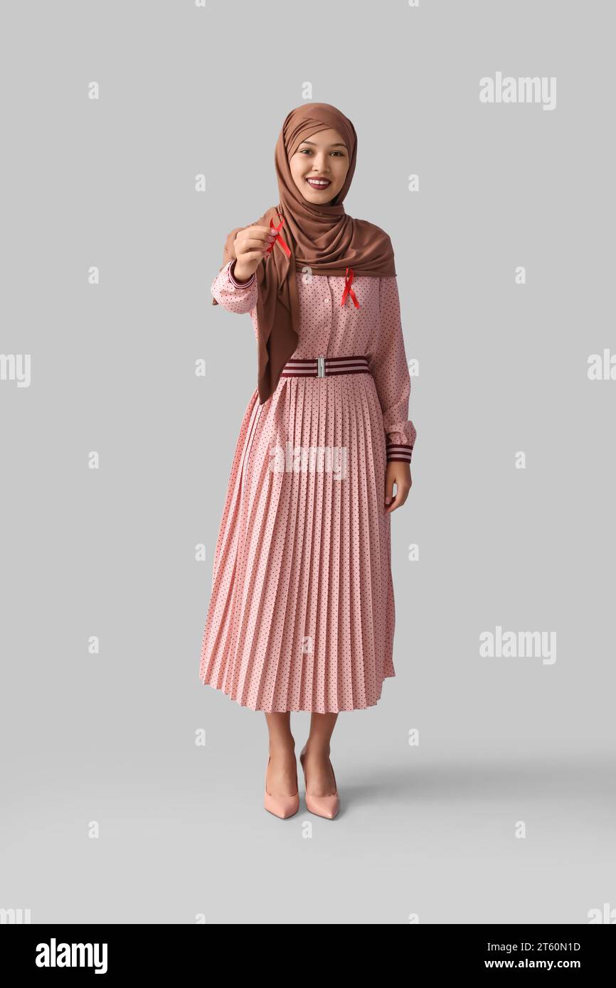 Beautiful Muslim woman with red ribbons on grey background. AID ...