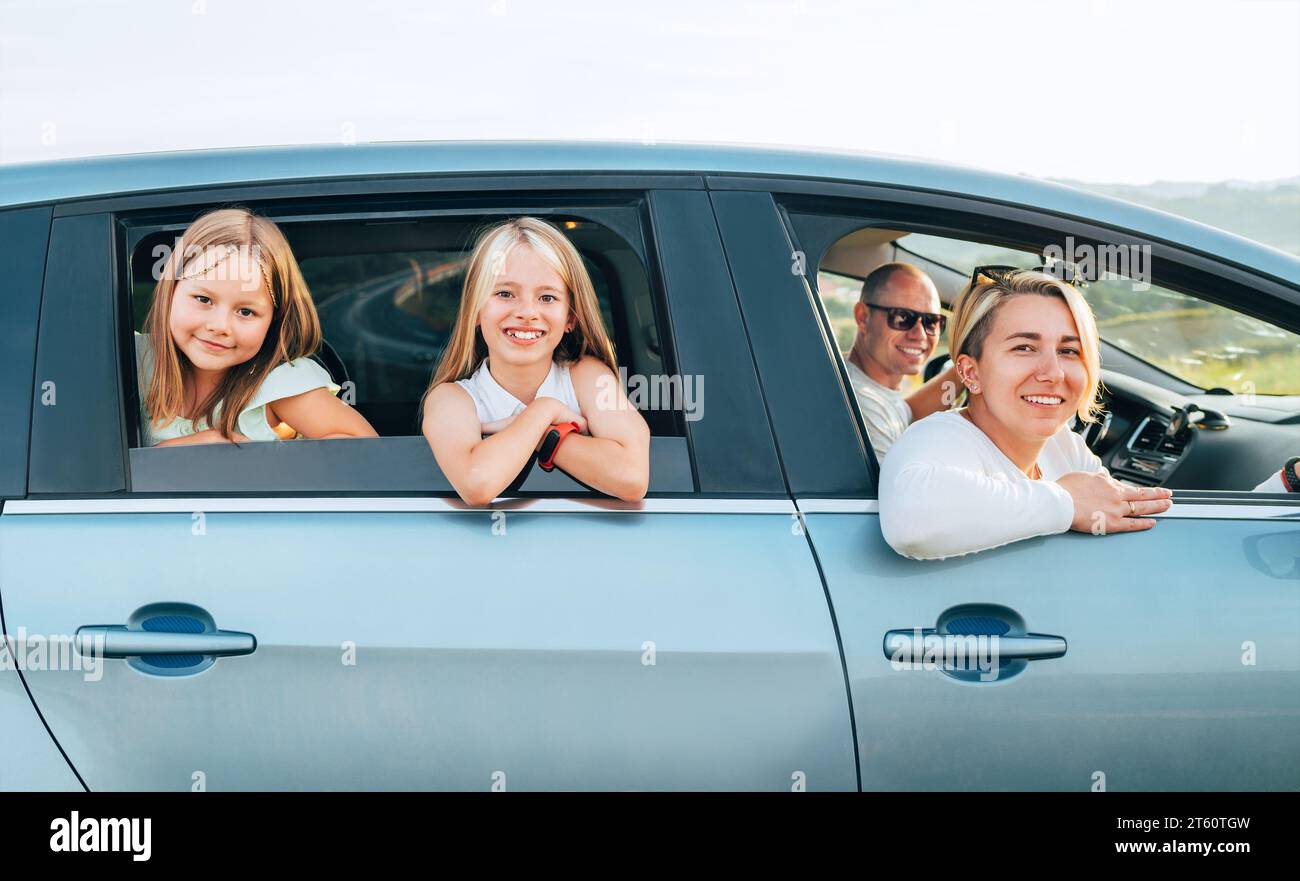 Happy young couple with two daughters inside car during auto trop. They ...