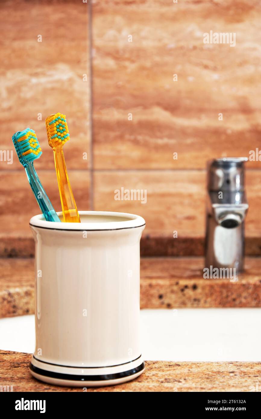 Vertical template with toothbrushes in the cup on the bathroom sink ...