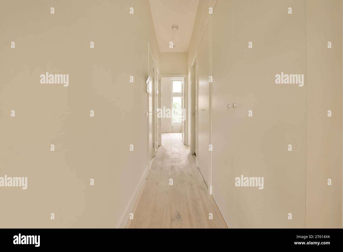 a long hallway with white walls and wood flooring on either side by ...