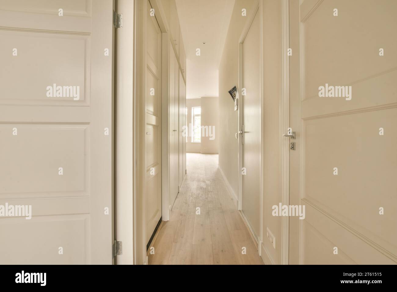 a long hallway with white walls and wood flooring on either side by ...