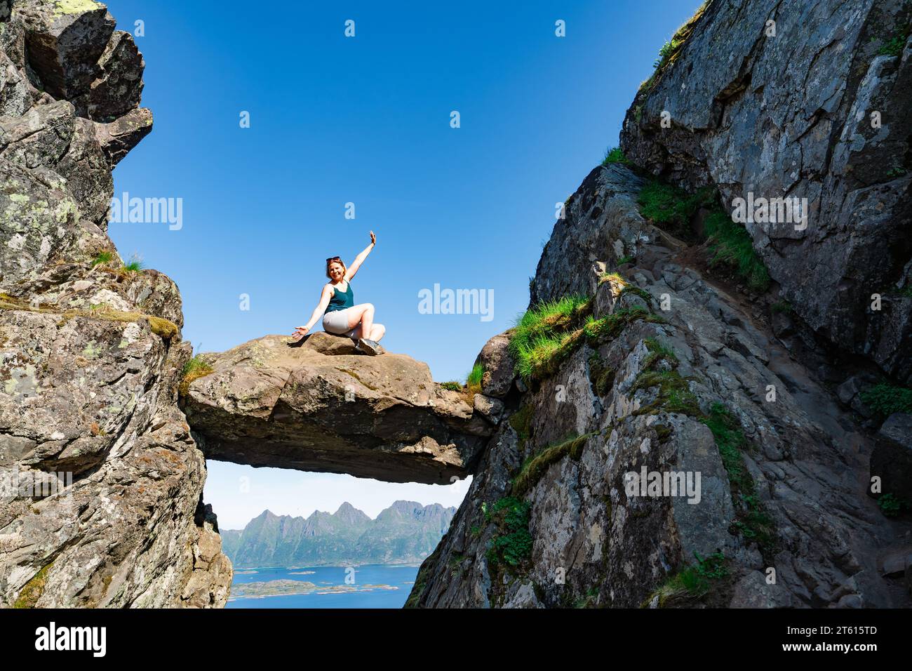 Brave traveler woman standing on hanging stone between rocks ...