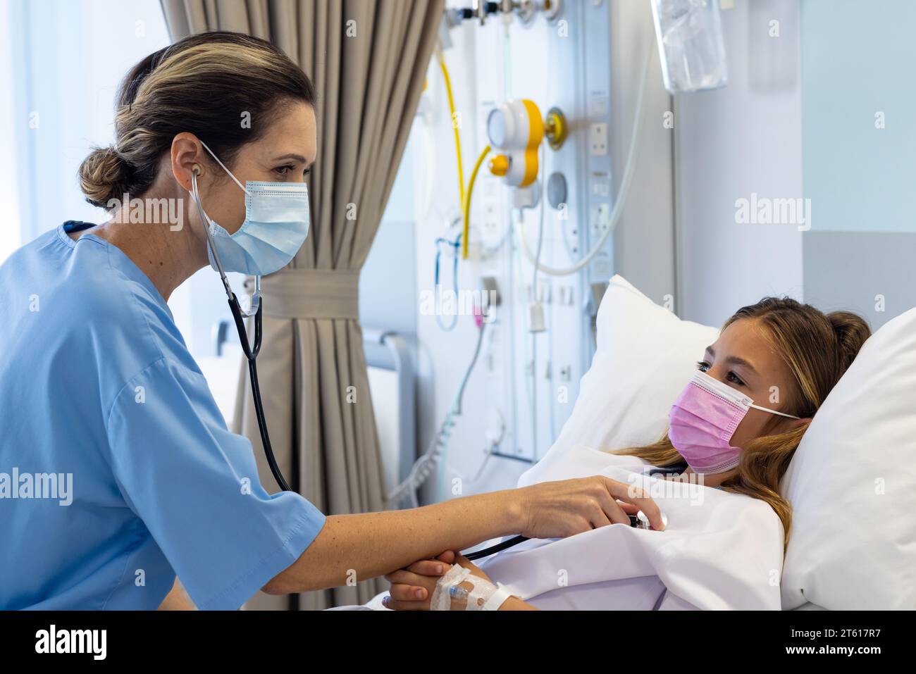 Caucasian female doctor using stethoscope on girl patient lying in ...