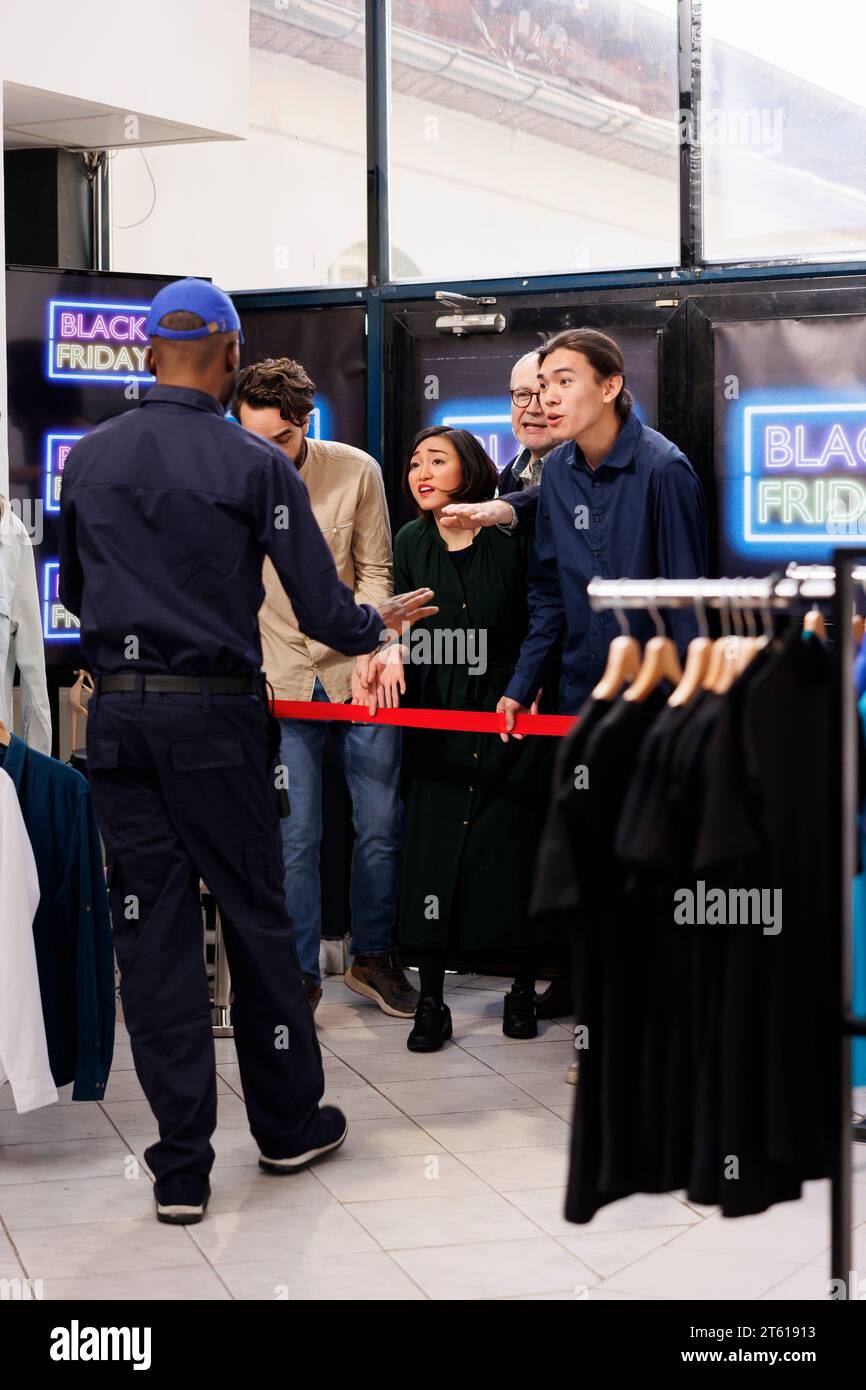Security guard keeping waiting shopper crowd in check before stores ...