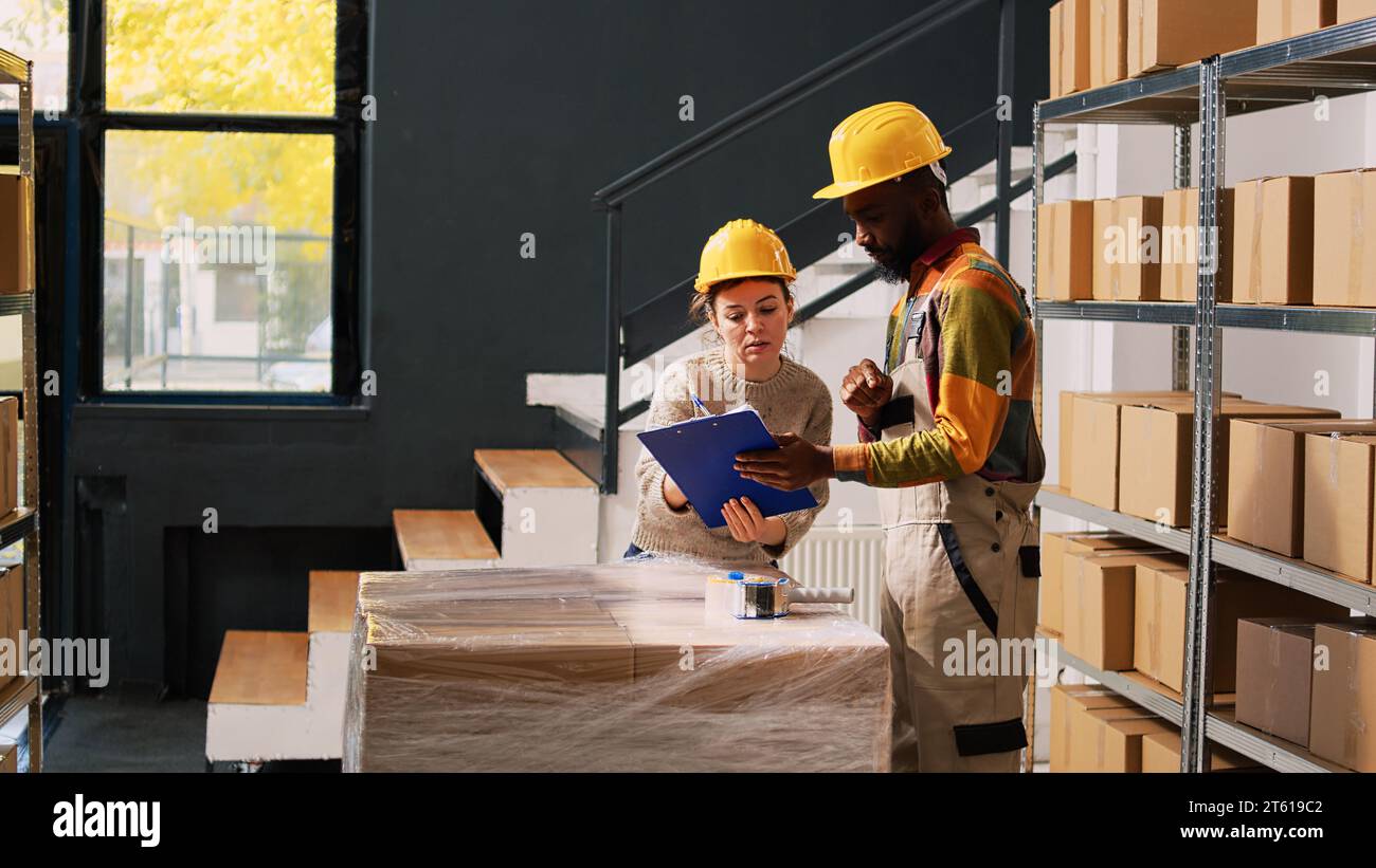 Warehouse team review shipping list in storage room, looking at stock ...