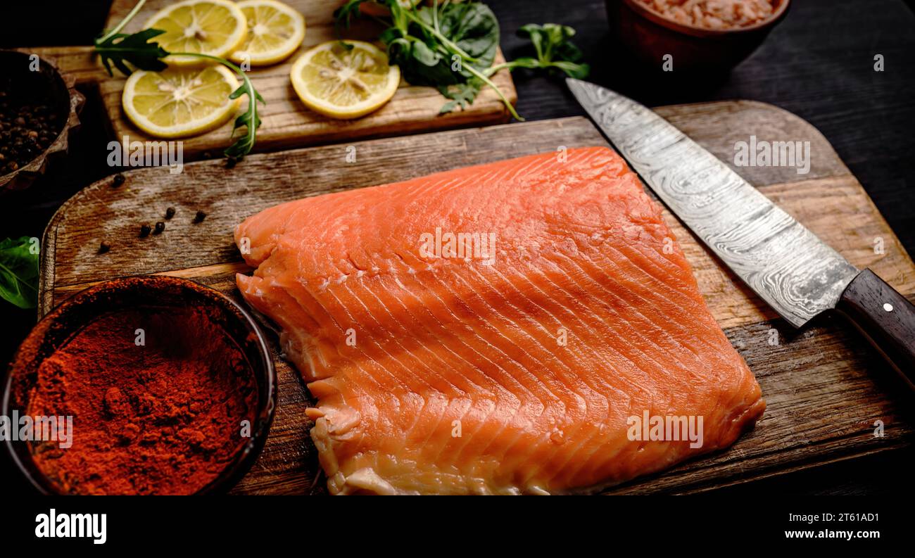 Raw salmon fillet with knife, spicies and lemons on wooden table ...