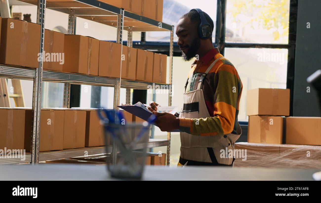 Male worker listening music in depot, working with merchandise stock in ...