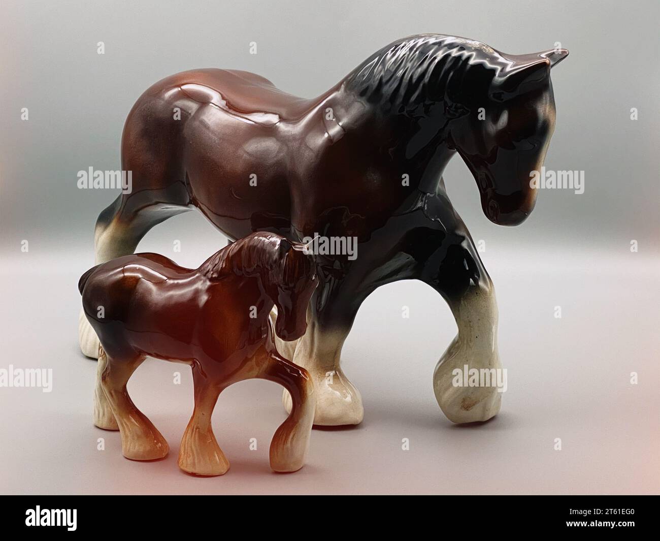 Two statues of rearing horses standing close together on a white table ...