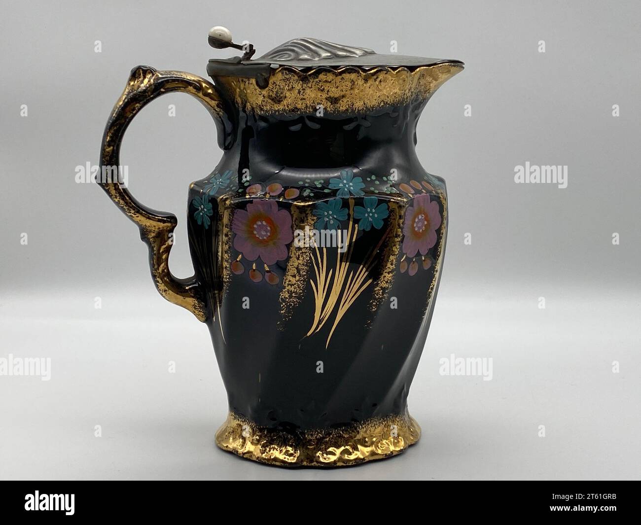 A classic ceramic pitcher with intricate gold detailing around the ...